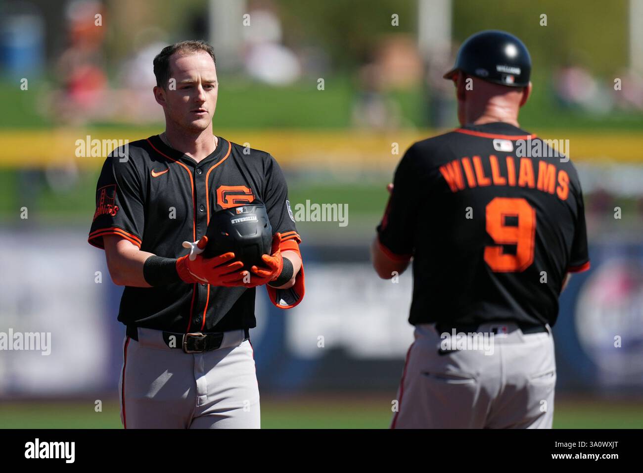San Francisco Giants' Tyler Fitzgerald, left, hands his batting helmet ...