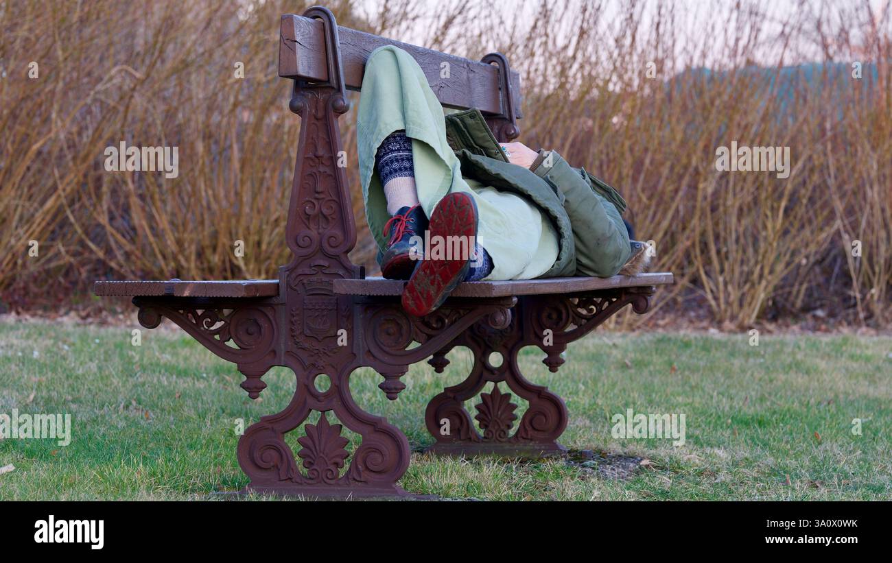 Woman sleeping on an ornamented park bench Stock Photo - Alamy