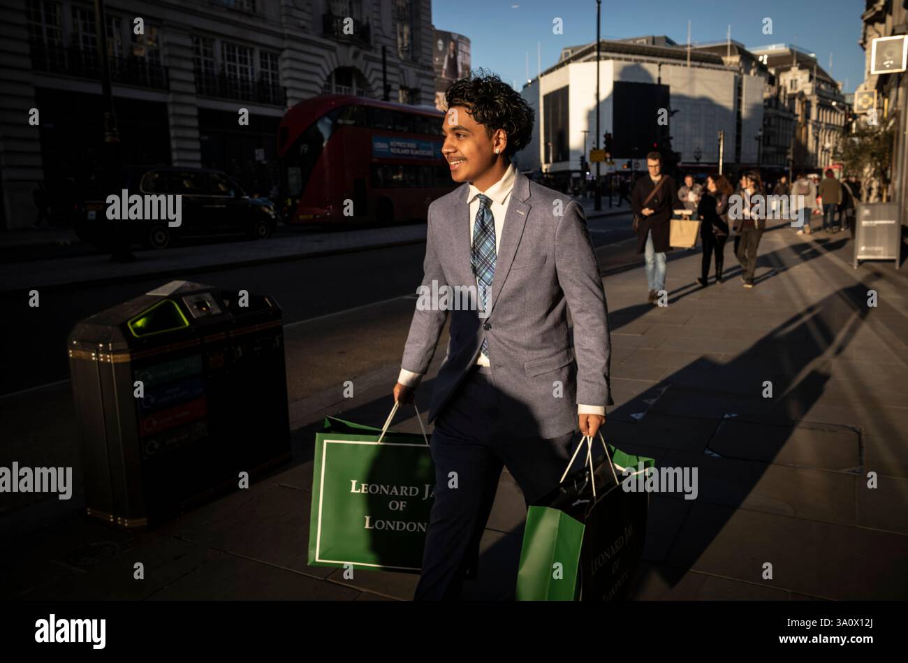 A young man carries clothes bags from Leonard Jay along Piccadilly ...