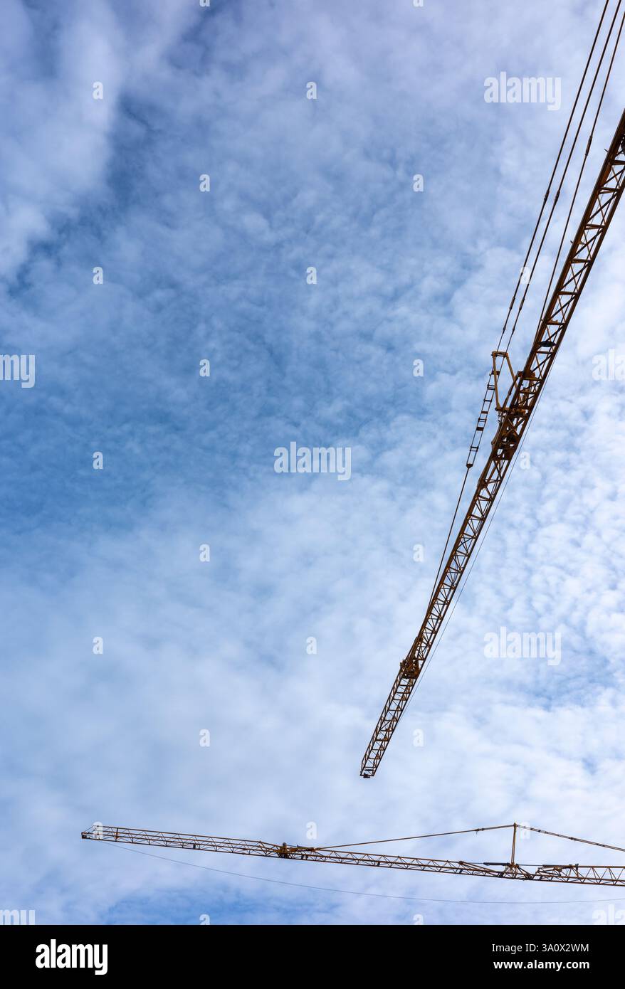 Long, vertical arms of the construction cranes in the background of ...