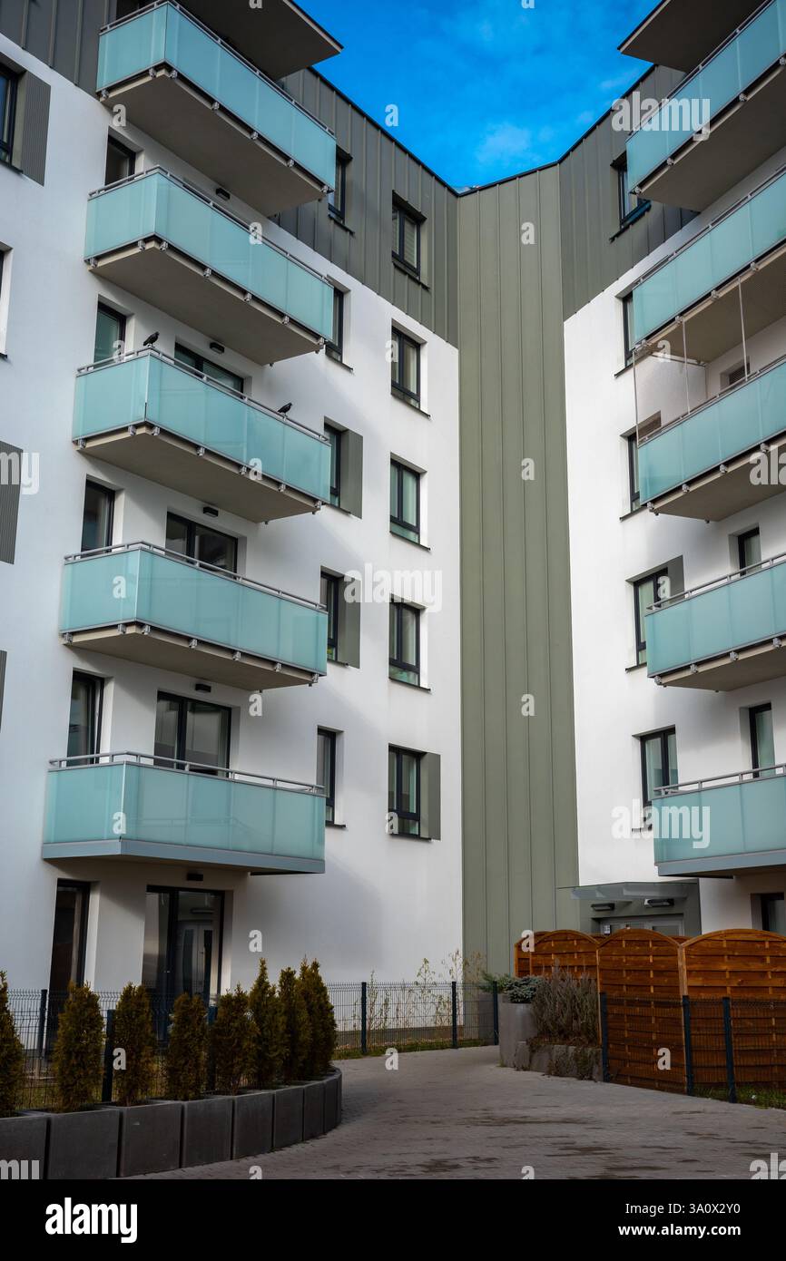 The light-gray facade of a modern apartment building against the blue ...