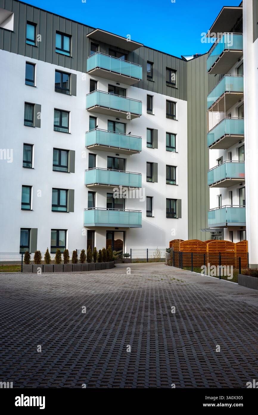 The light-gray facade of a modern apartment building against the blue ...