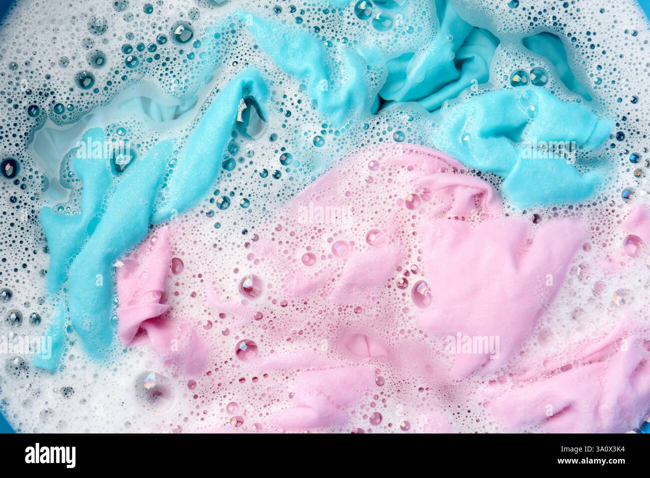Colorful clothes soaked in water before washing, top view Stock Photo ...