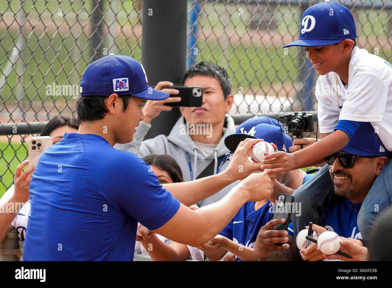 Los Angeles Dodgers' Shohei Ohtani hands an autographed baseball to a ...