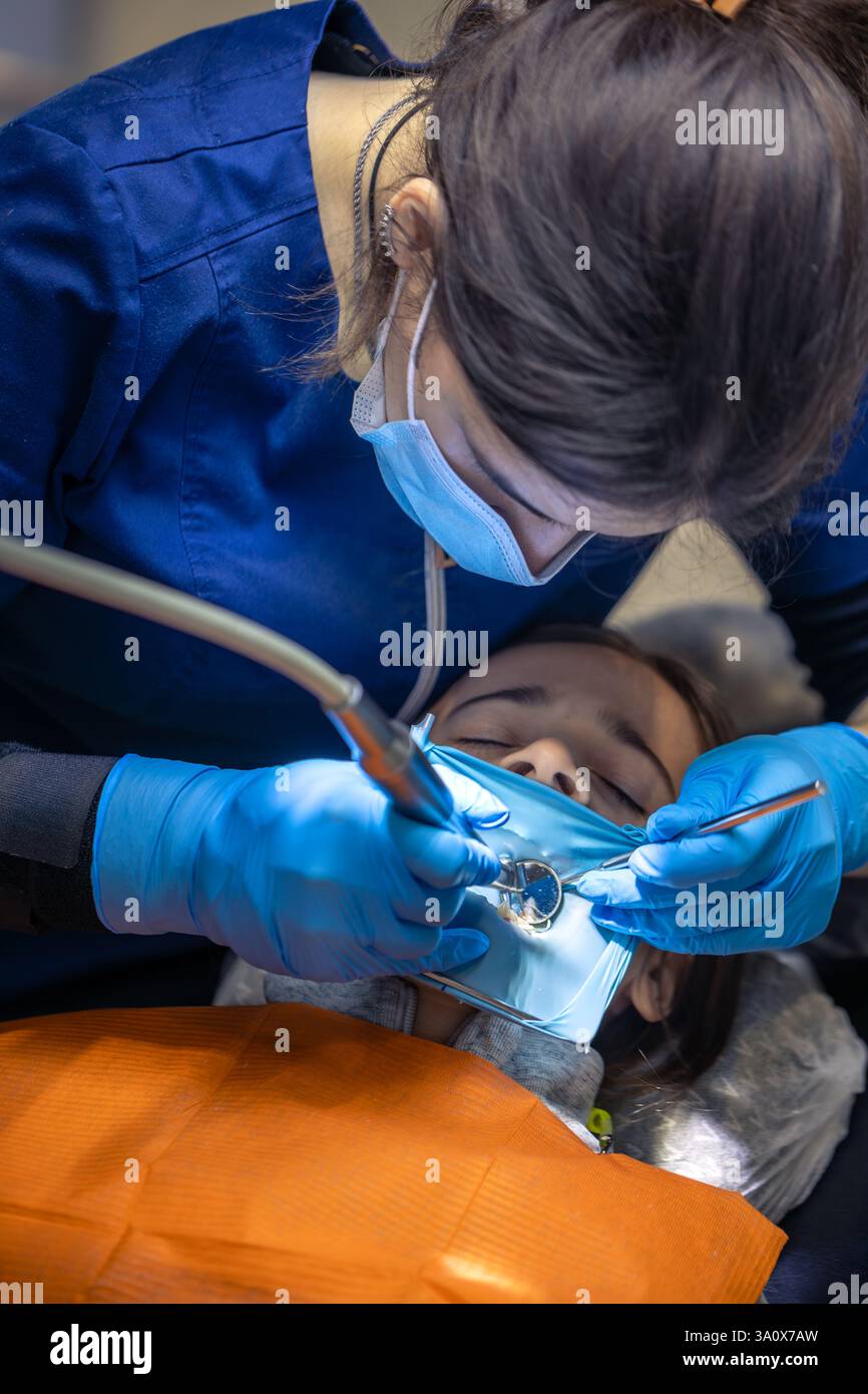 The dentist treats the child's tooth using a rubber dam. Close-up of ...