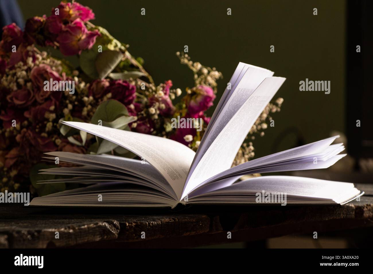 Open book on wooden table at home with dry roses bouquet in room Stock ...