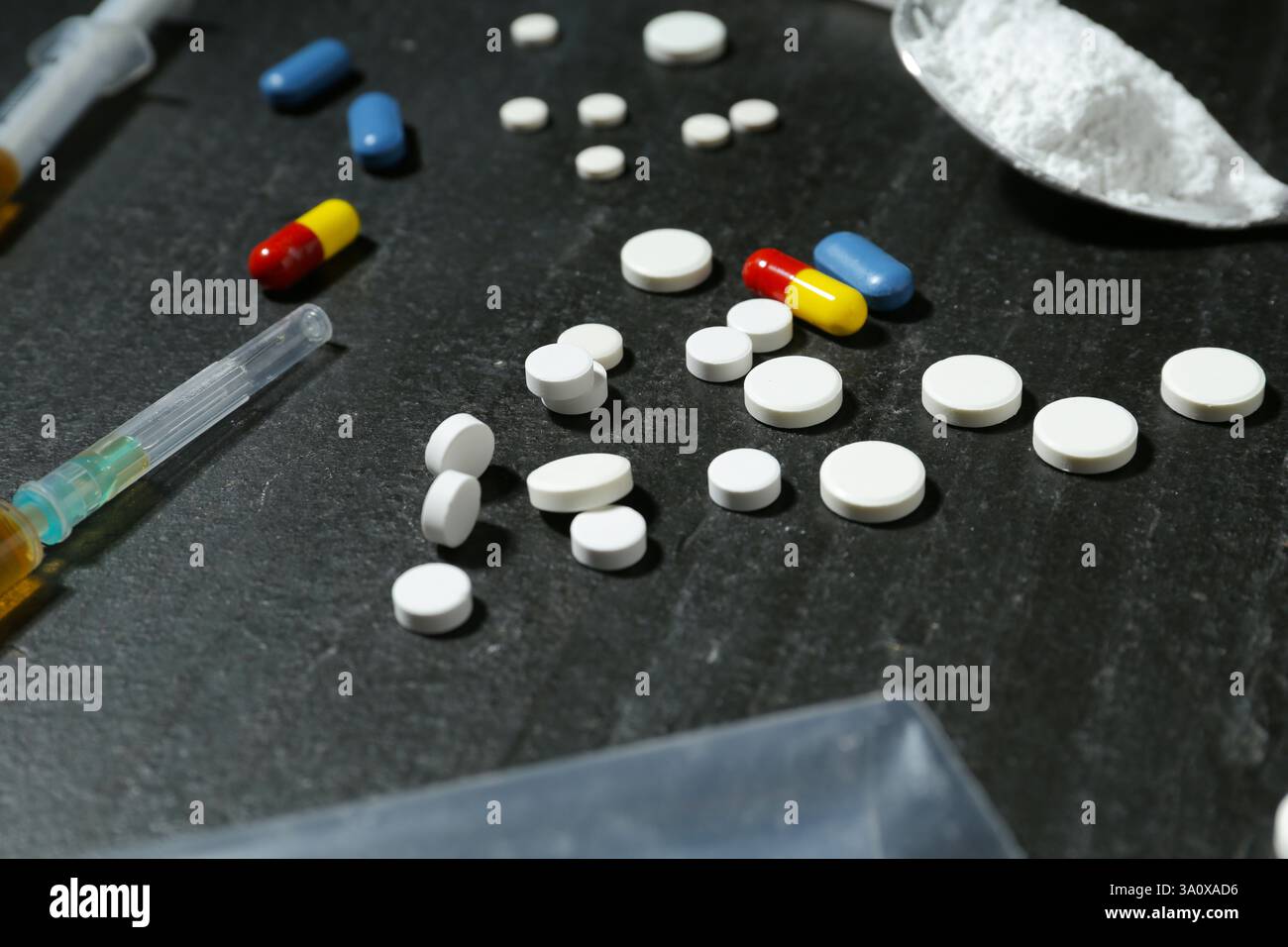 Drug addiction. Pills, syringes and spoon with powder on dark textured ...