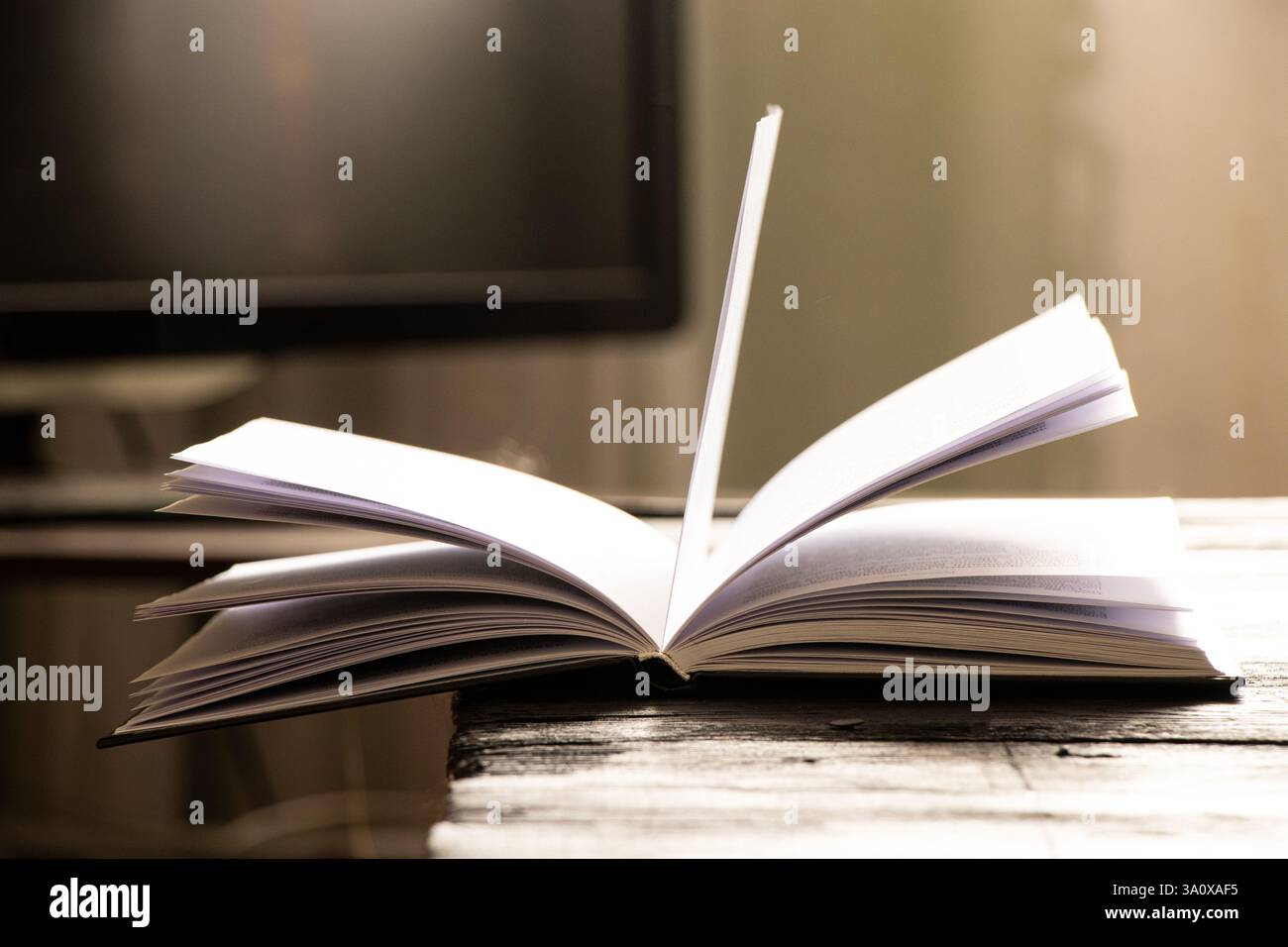 An open book on a table at home in the light, read Stock Photo - Alamy