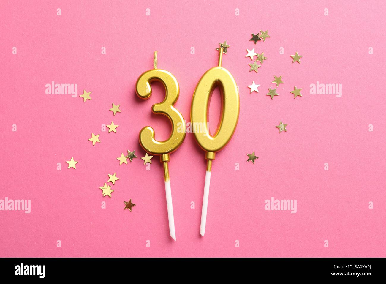 30th birthday. Number shaped candles and confetti on pink background ...