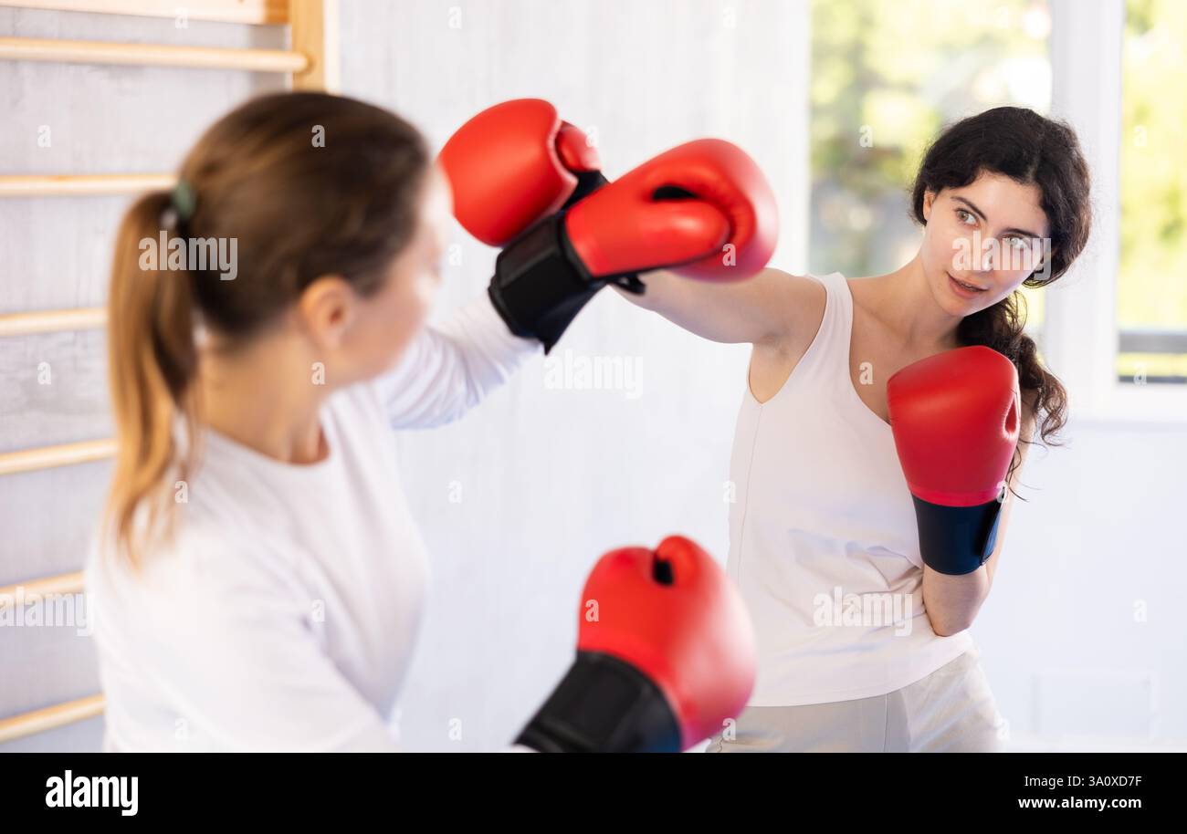 Focused woman practicing boxing punches in sparring during group self defence course Stock Photo ...