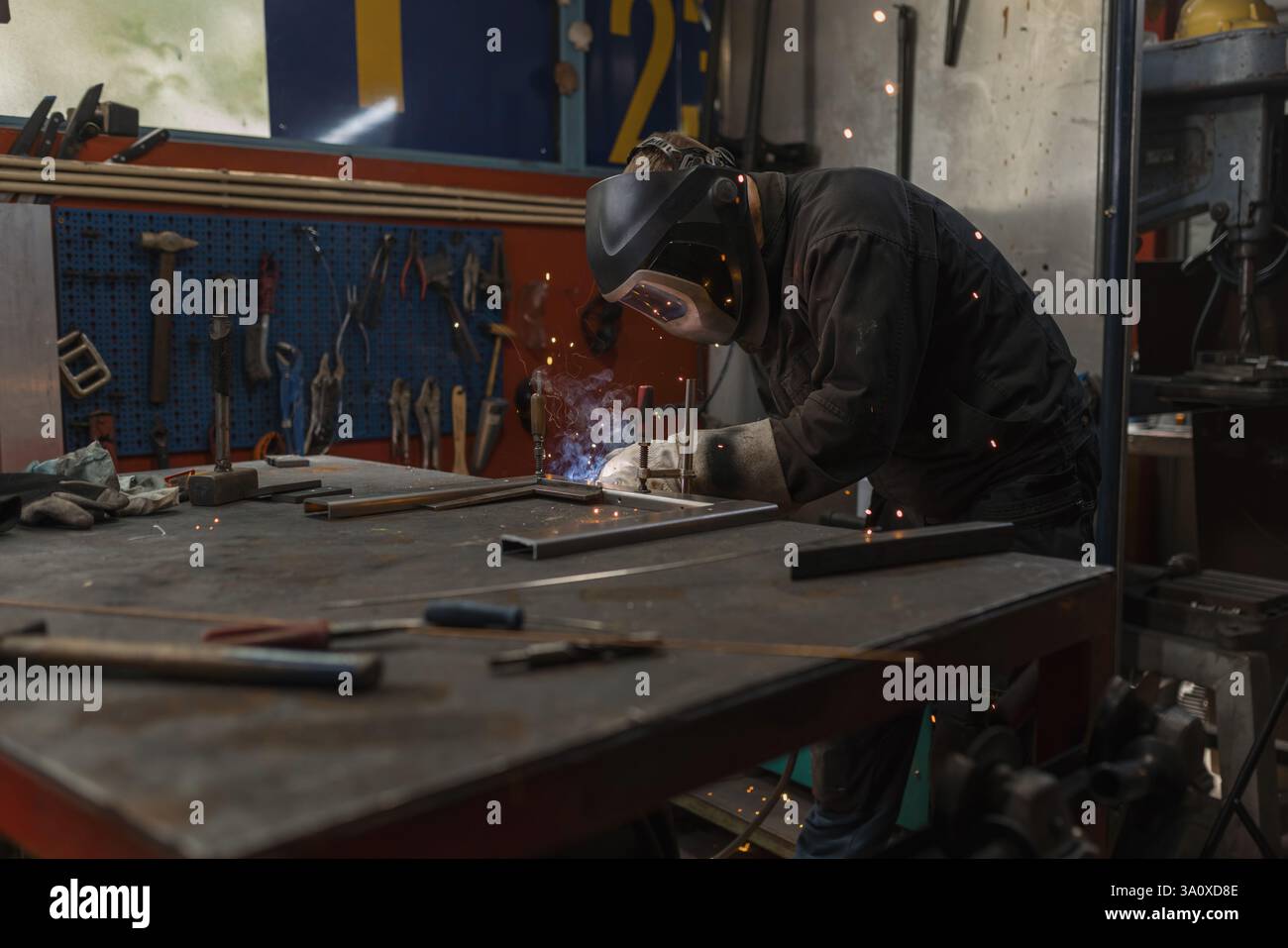Worker wearing a protective helmet and gear during the welding process ...