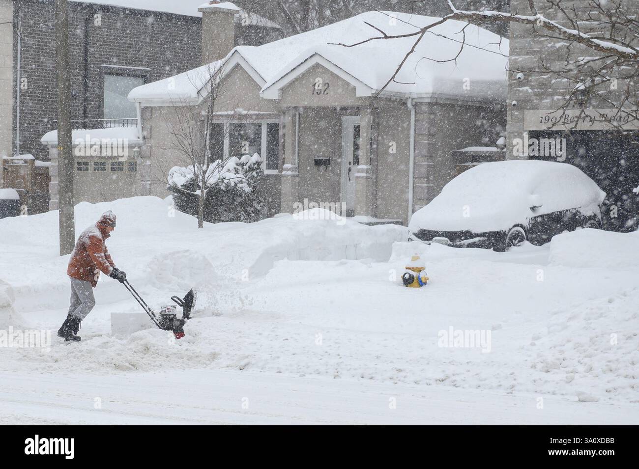 Toronto, ON, Canada - February 27, 2025: A man uses a snow blower to ...