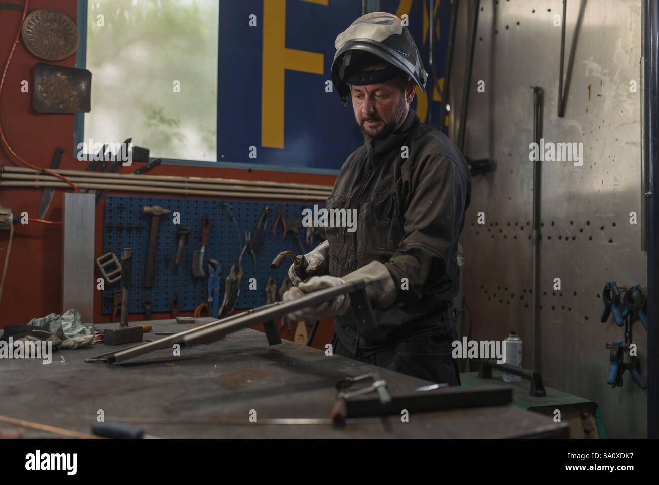 Worker wearing a protective helmet and gear during the welding process ...