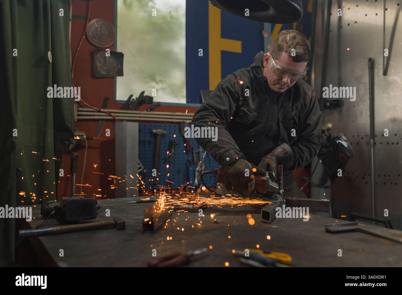 Welder processing a metal pipe with a grinder, making sparks. Metalwork ...
