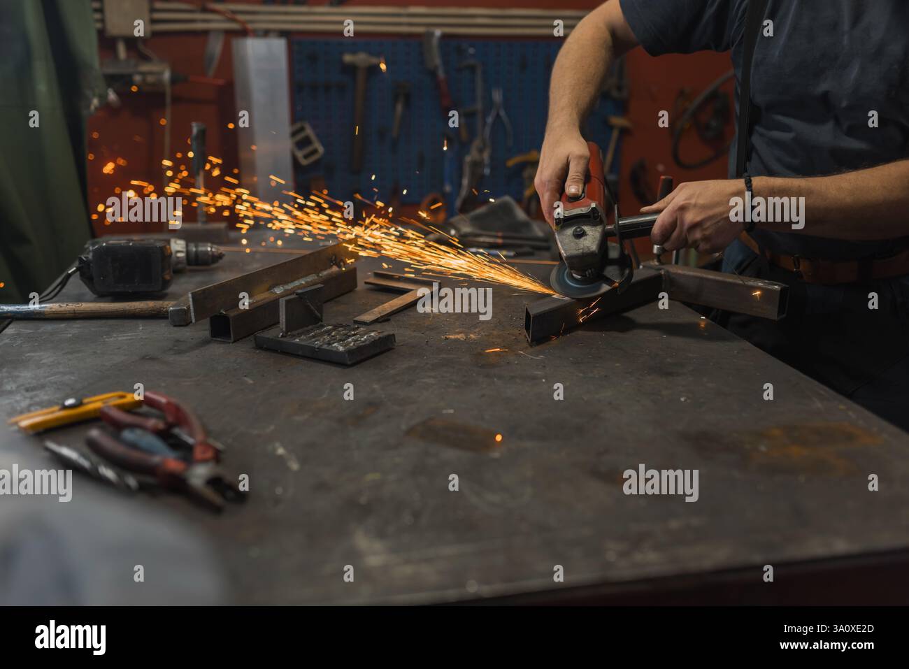 Welder processing a metal pipe with a grinder, making sparks. Metalwork ...