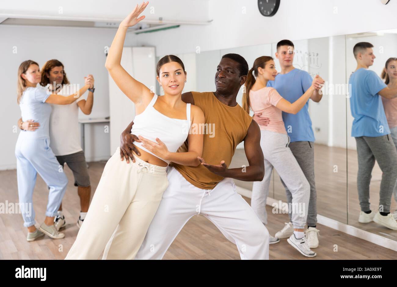 Joyful young adult couples learning passionate pair dancing during ...
