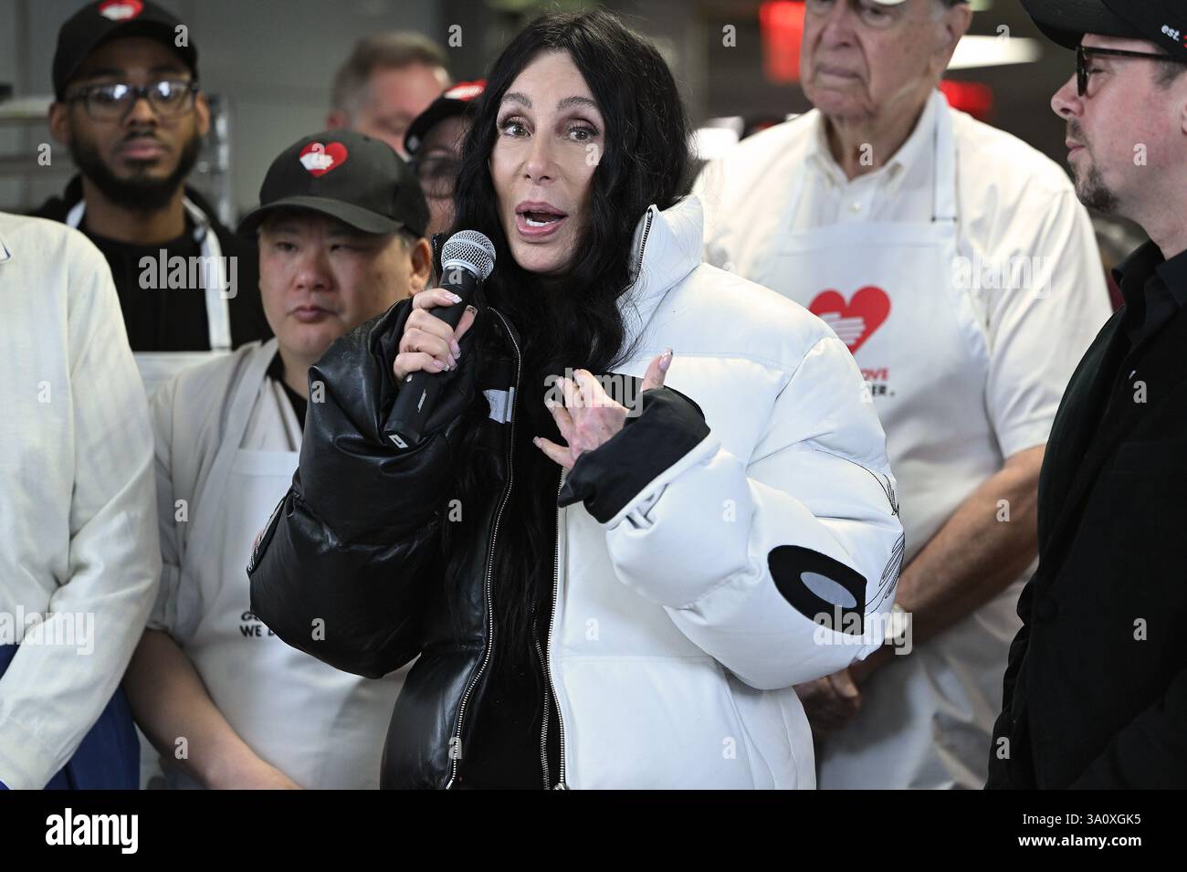 New York, USA. 05th Mar, 2025. American singer Cher (center) visits with volunteers and kitchen ...