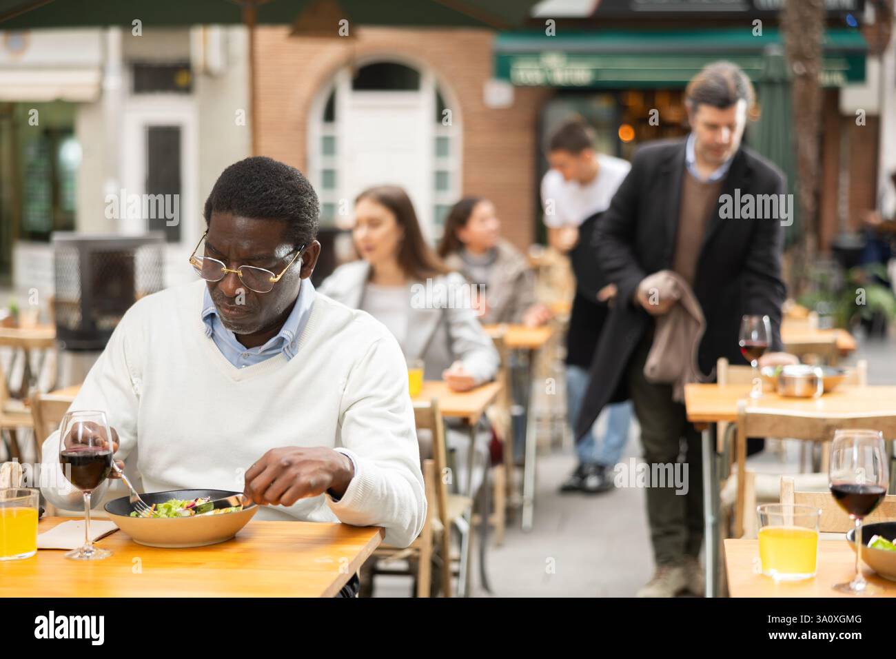 On open area of cafe, African man in restaurant eating salad Stock ...