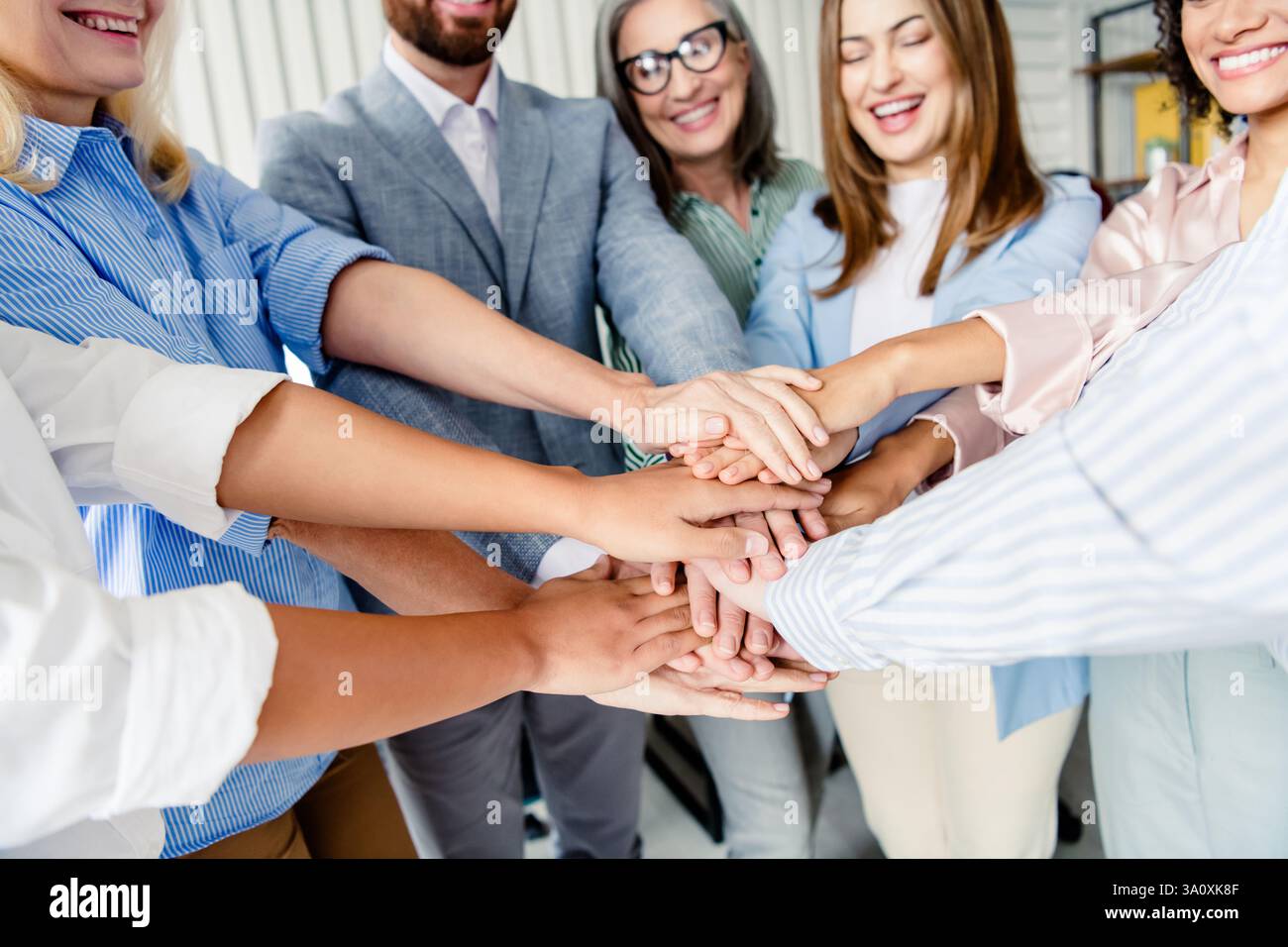 Group of professionals joining hands in a collaborative office setting ...