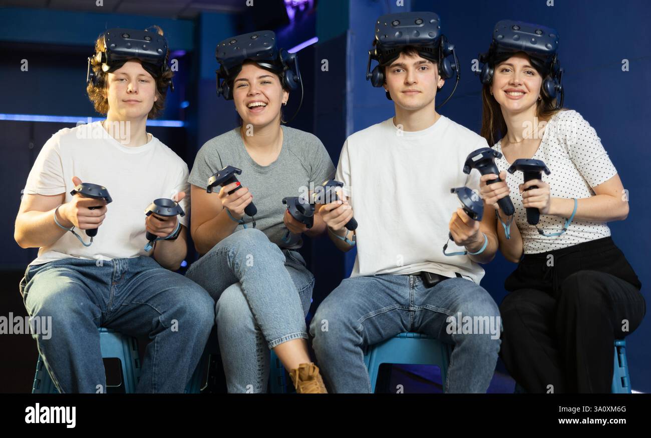 four smiling students with virtual reality devices sit and pose in ...