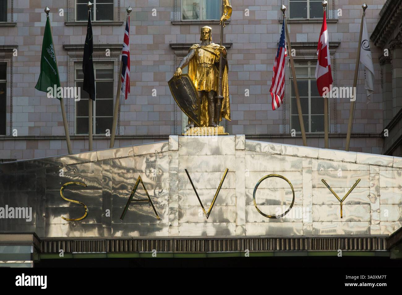 The Savoy Hotel. Gold statue of a knight atop the facade, with flags of ...
