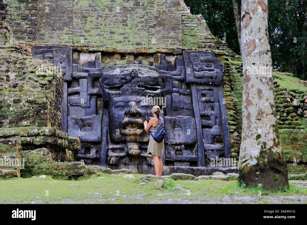 A female visitor in front of Mask Temple in Mayan archaeological site ...