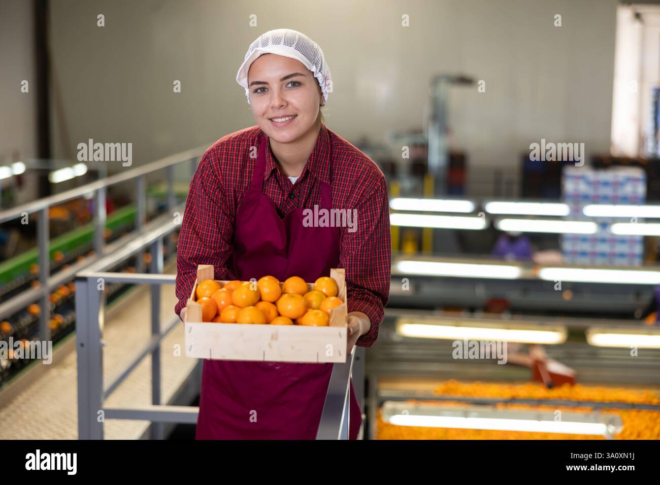 Glad positive female employee in colored uniforms hold a box of fresh ...