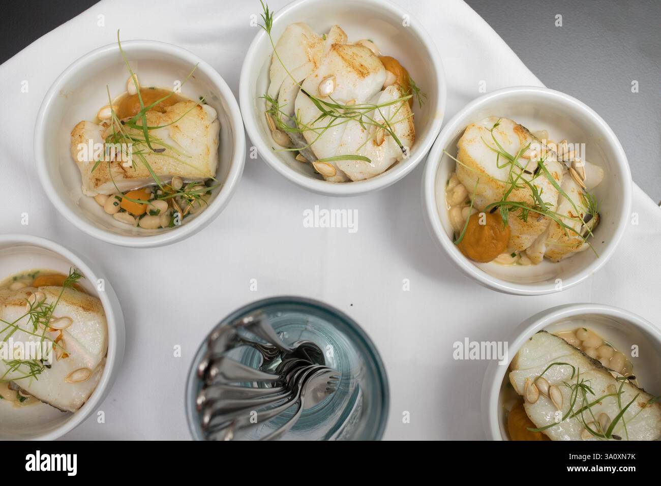 Small plates of pan-seared cod with white beans, purée, and pumpkin ...