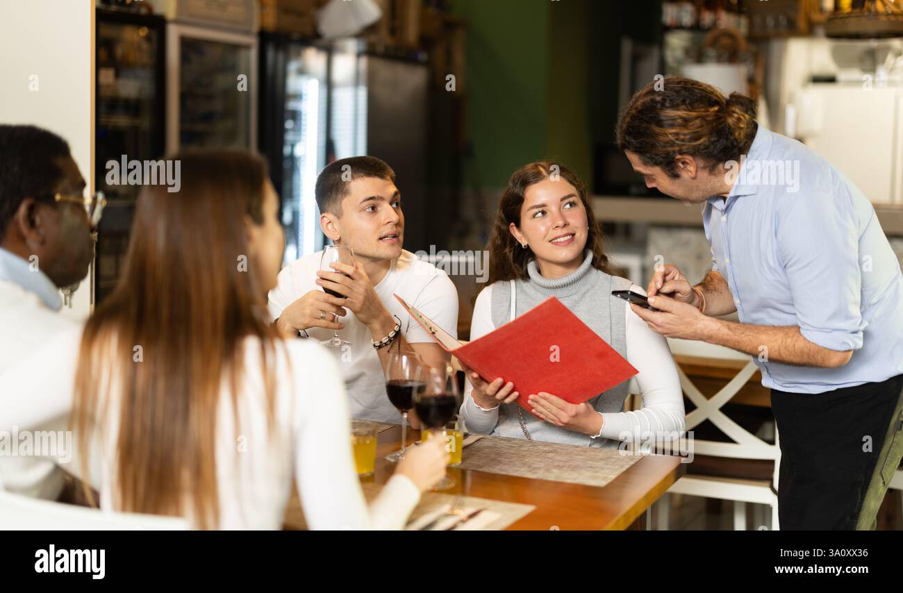 Man waiter writes down girls order. Employee serve couple clients in ...