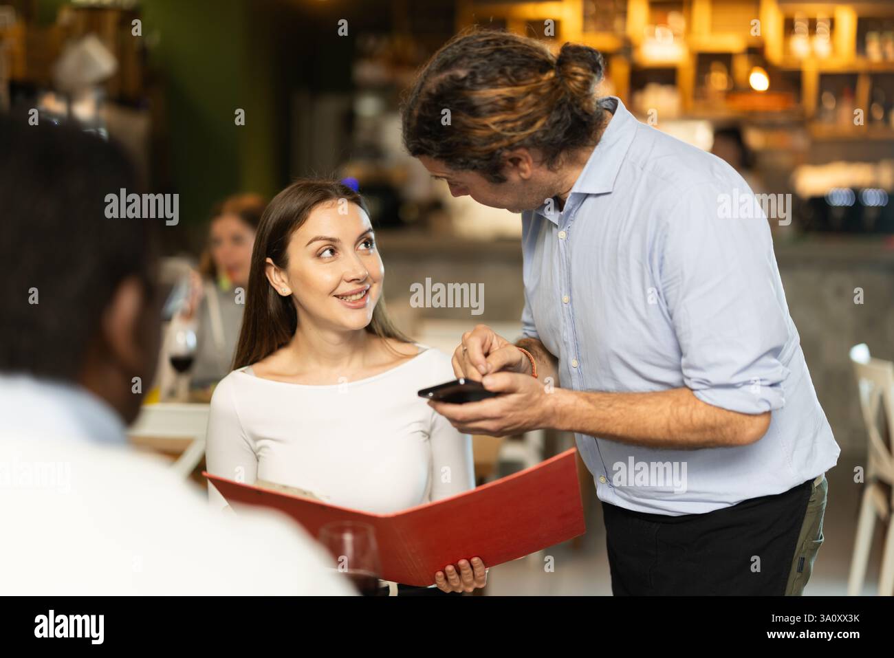 Man waiter writes down girls order. Employee serve couple clients in ...