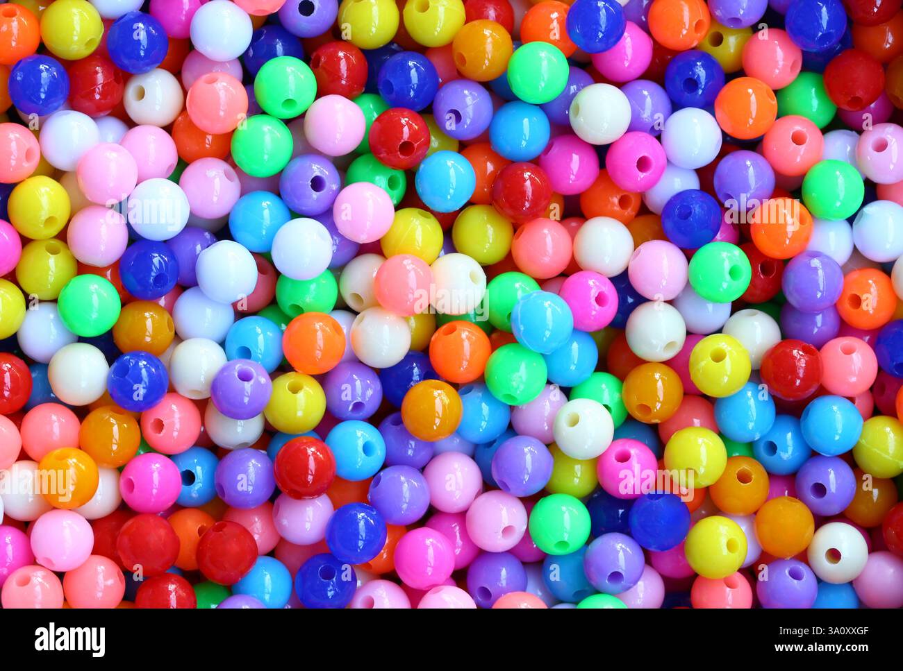 A vibrant collection of small plastic beads in a rich spectrum of ...