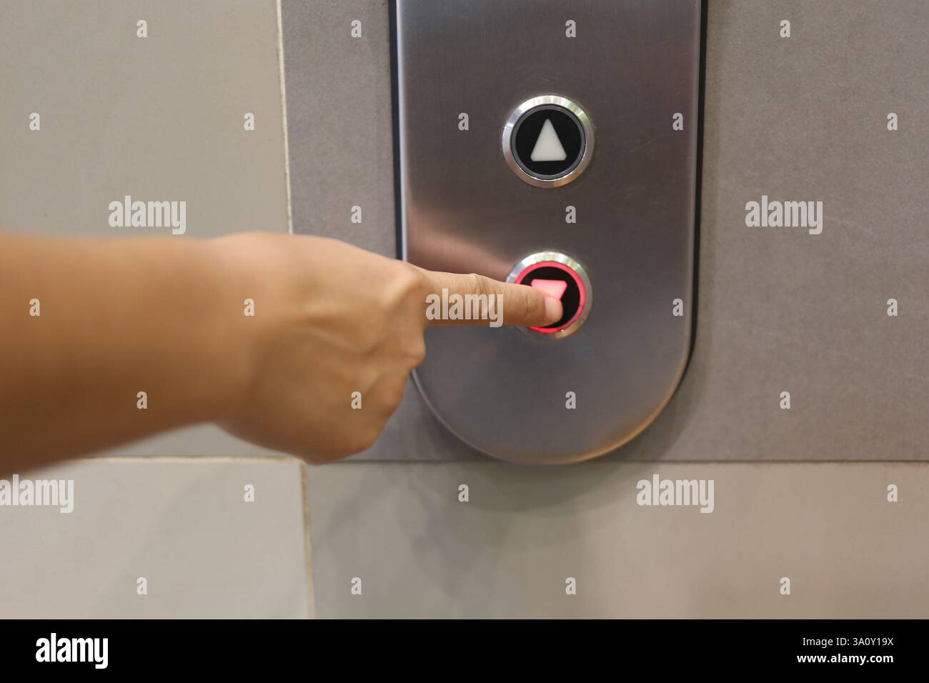 Close-up view of a hand pressing an elevator button in a modern ...