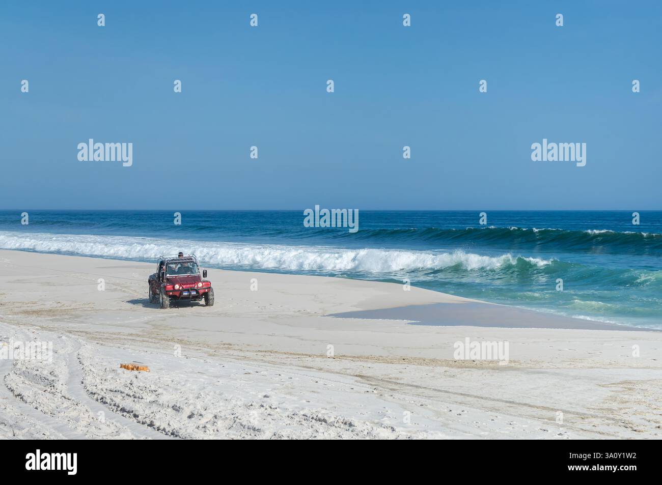 A red dune buggy passing by Praia Seca beach soft white sands with ...
