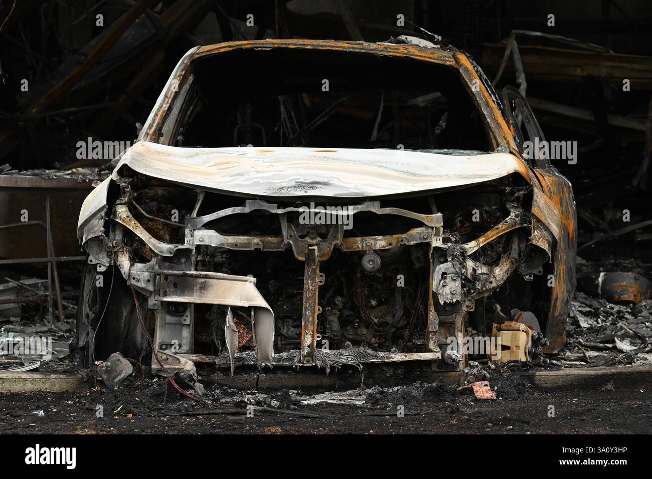 A burnt out car is seen in the shop front at the scene of a factory ...