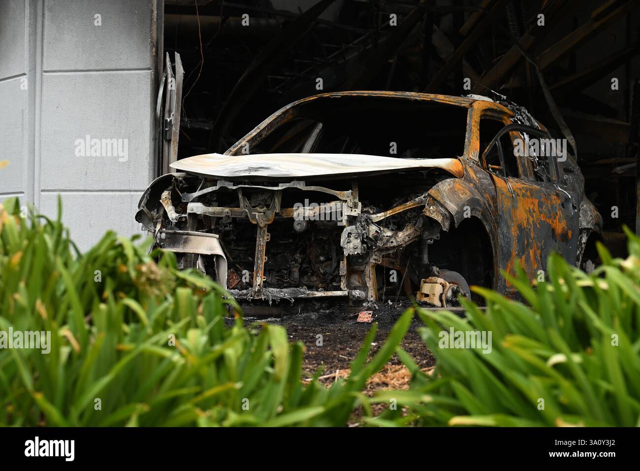 A burnt out car is seen in the shop front at the scene of a factory ...