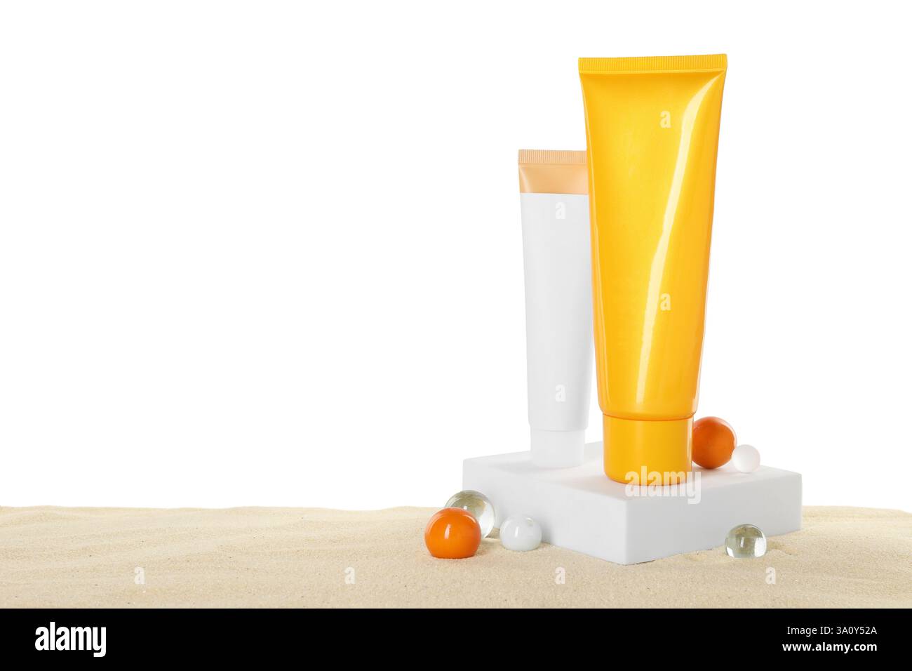 Tubes of sun protection product and decorative stones on sand against ...