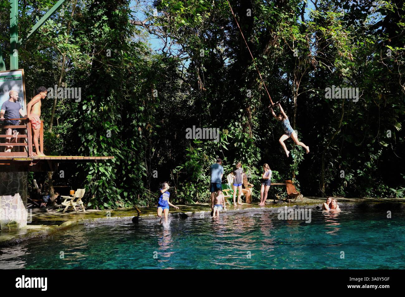 Tourist rope swing into the underground volcanic spring water pool of ...