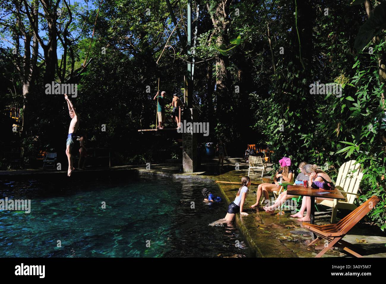 Tourist rope swing into the underground volcanic spring water pool of ...