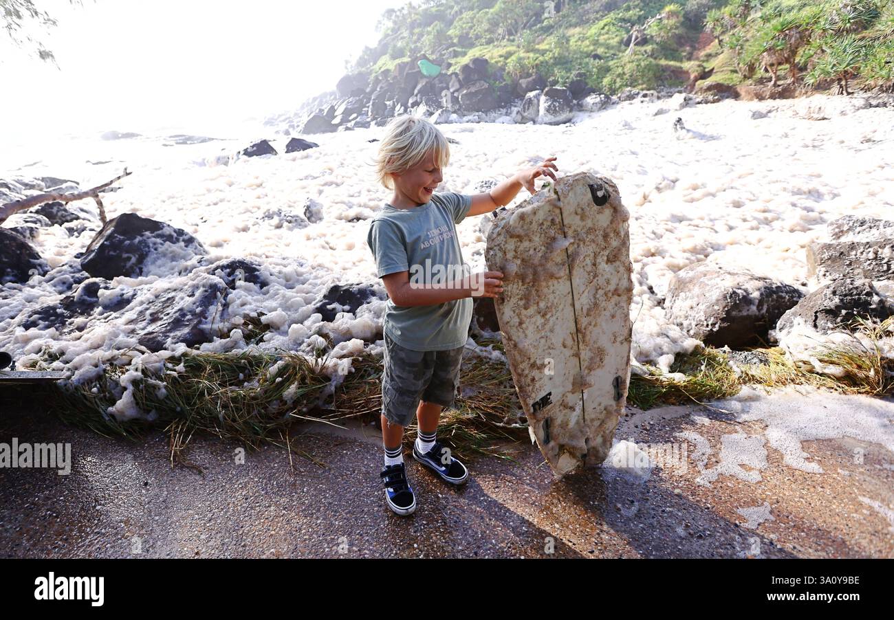 A young boy finds a broken surfboard after Big Seas from Tropical ...