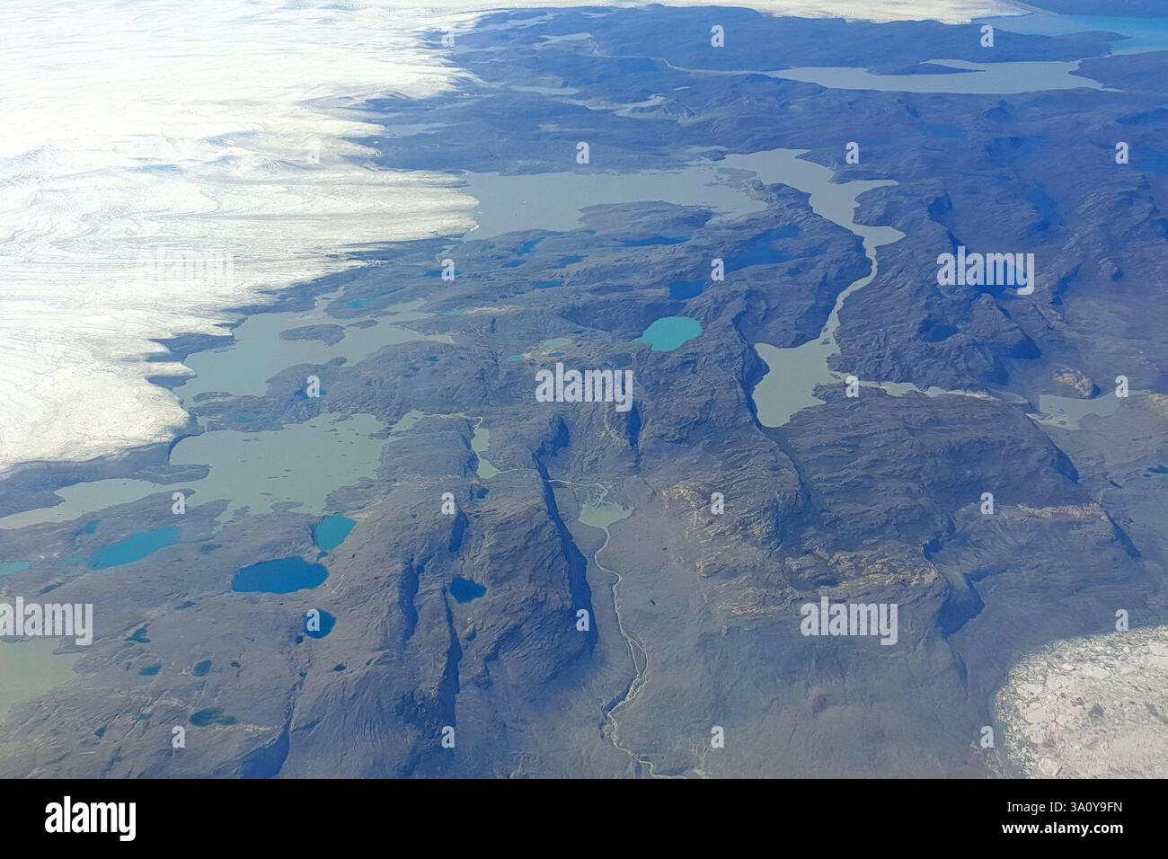 Aerial view from the plane window to the deserted expanses of Greenland ...