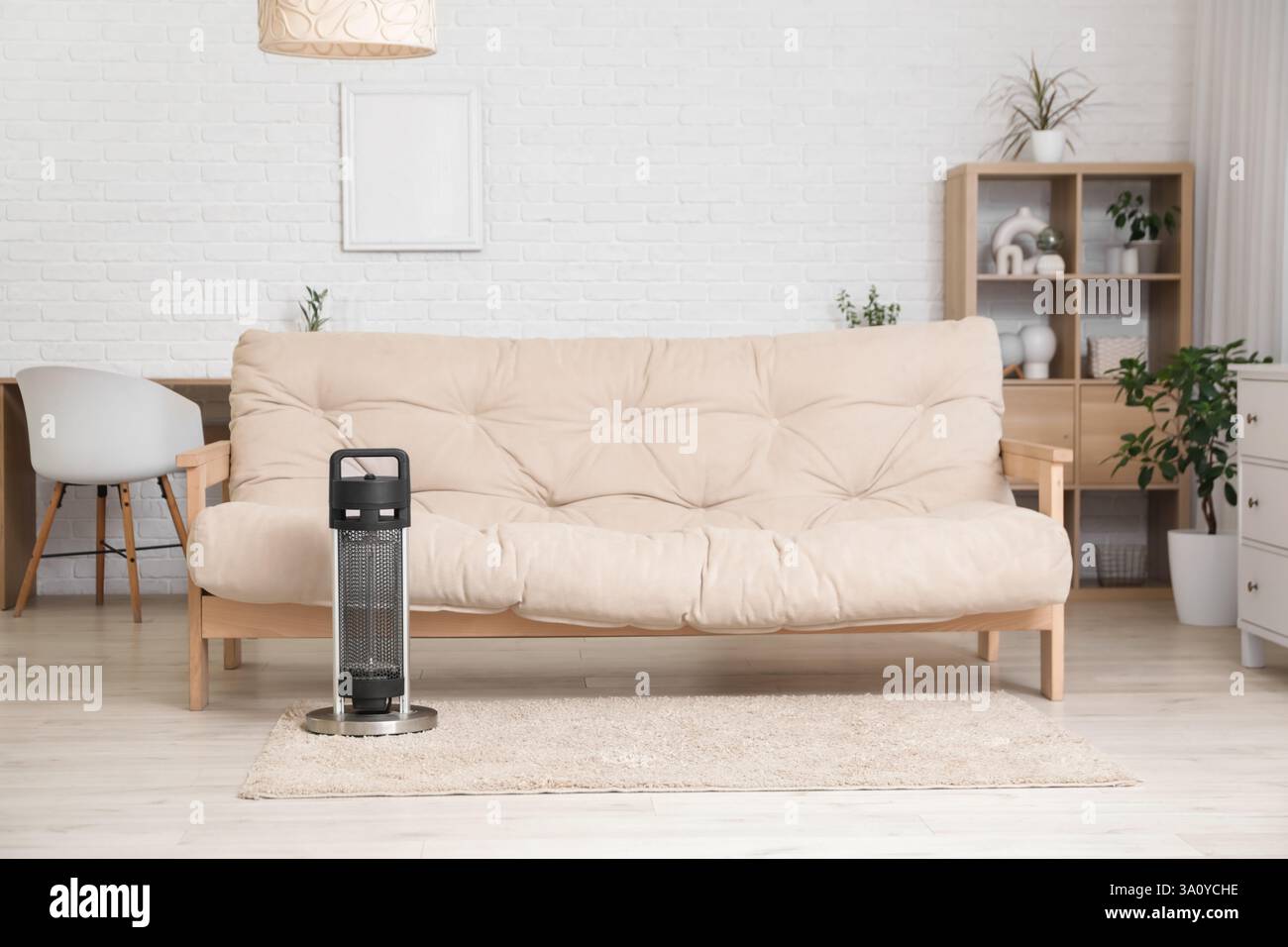 Electric heater on floor near sofa in living room Stock Photo - Alamy