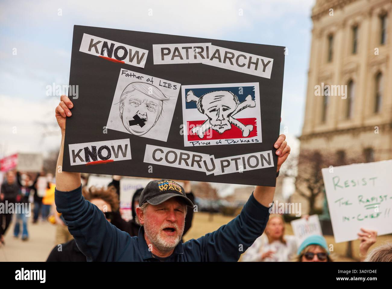 A protester holds a sign reading “Know patriarchy, know corruption ...