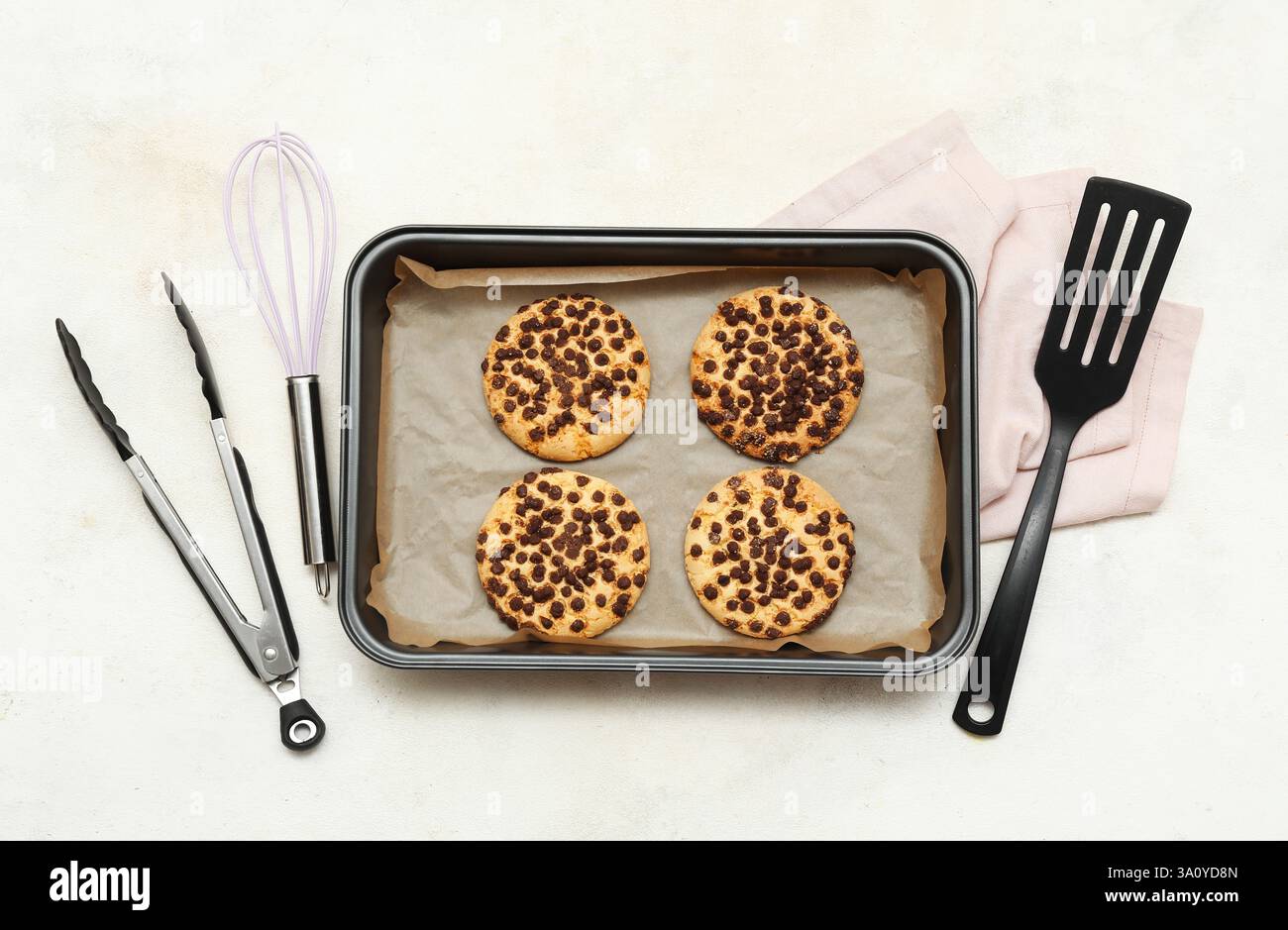 Baking tray with cookies on parchment paper, tongs, whisk, slotted ...