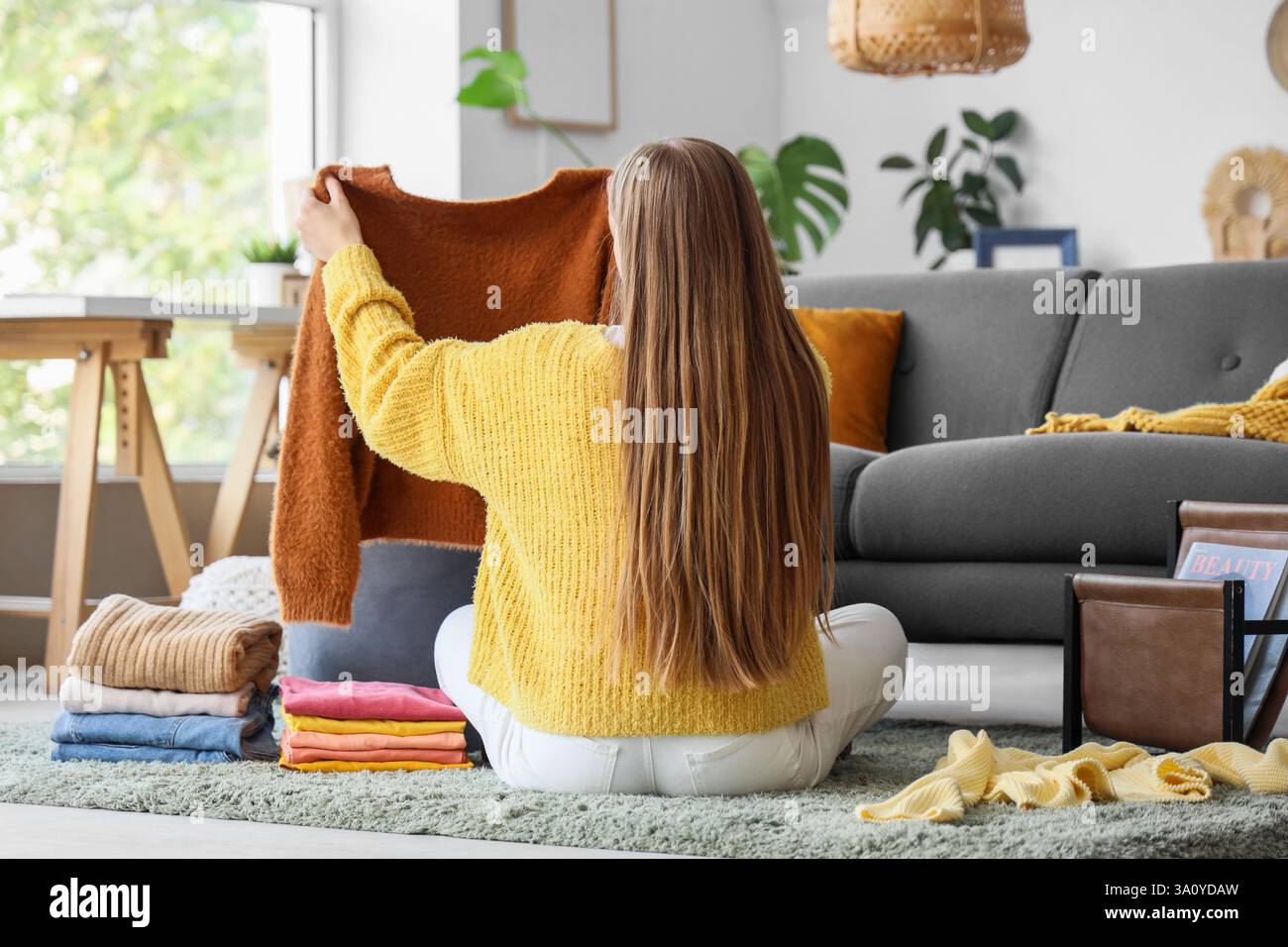 Young woman folding clean clothes into stacks at home, back view Stock ...
