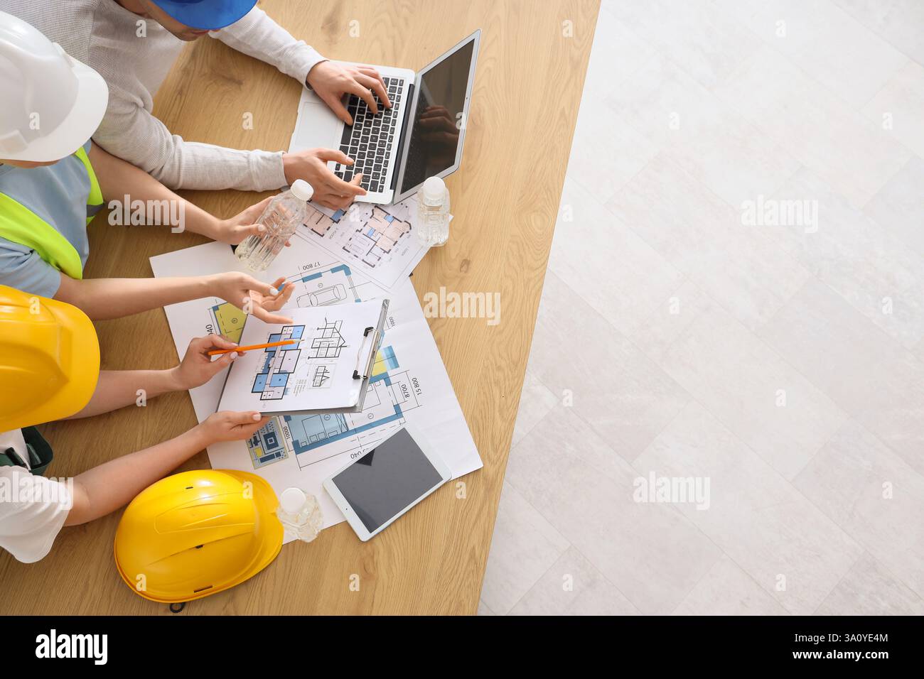 Team of constructors working with laptop and house plan at table in ...