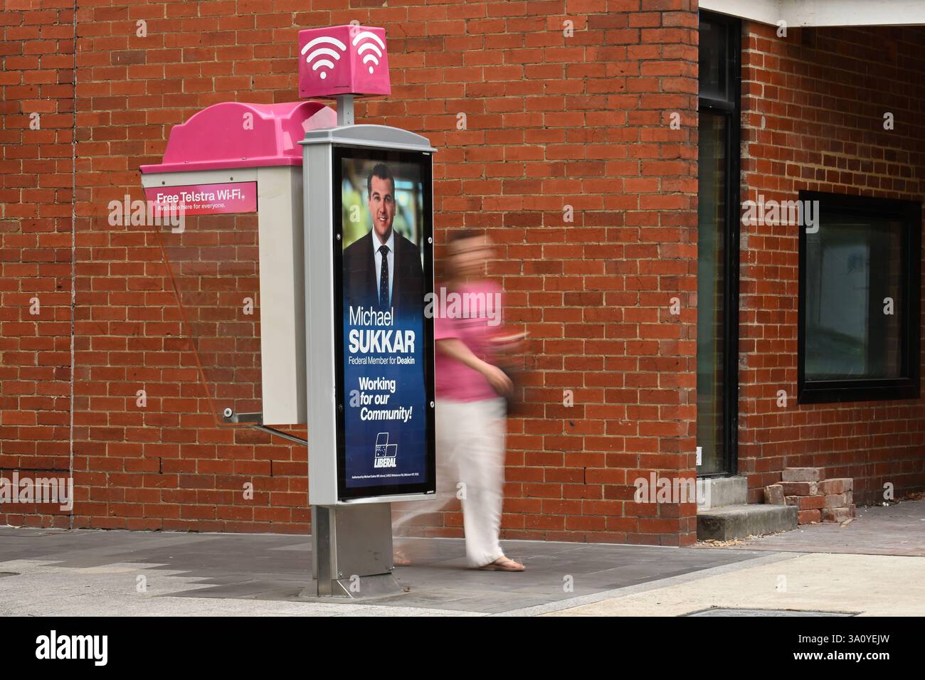 A person is seen walking past an advertisement for Michael Sukkar MP ...