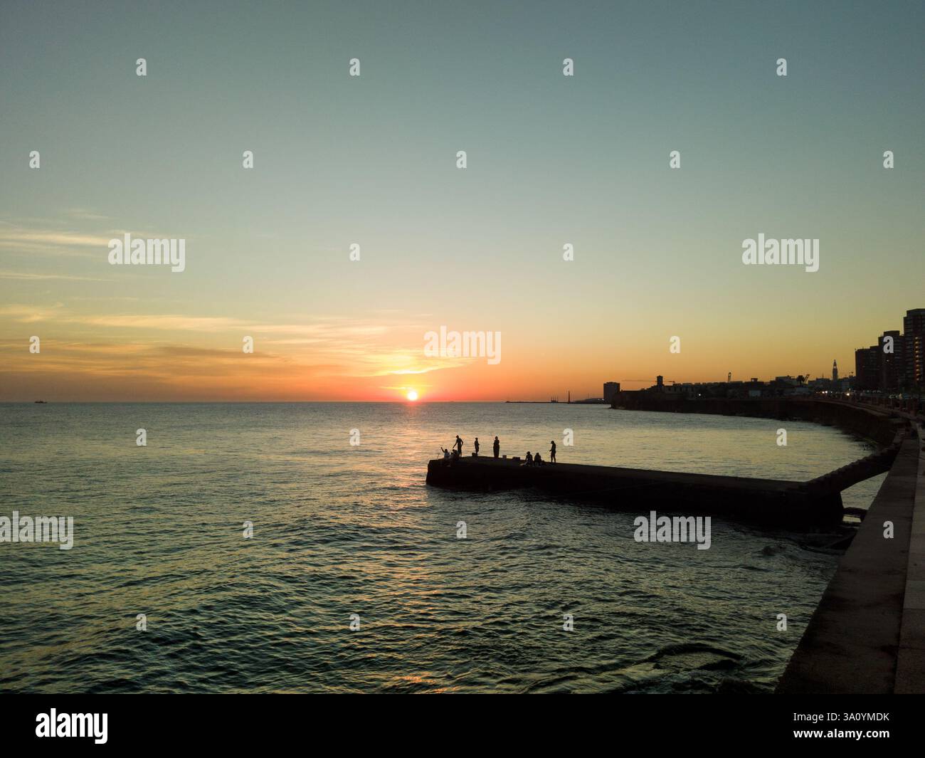 A pier with fishermen in silhouette in the city of montevideo with ...