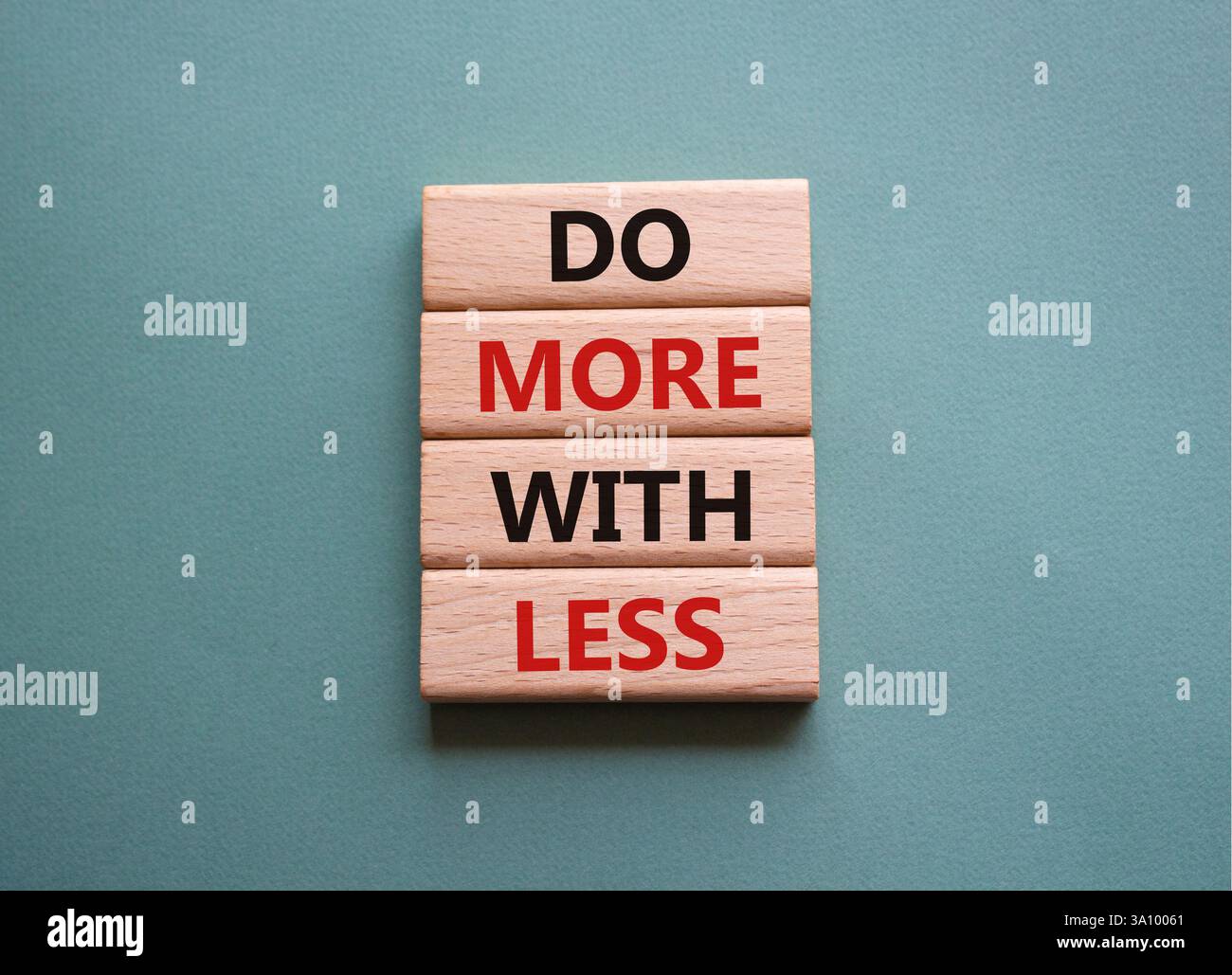 Do more with less symbol. Concept words Do more with less on wooden blocks. Beautiful grey green ...