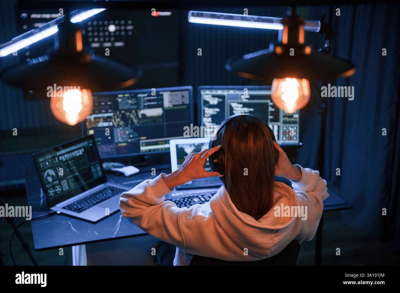 Looking at screens. Young professional female hacker is indoors by ...
