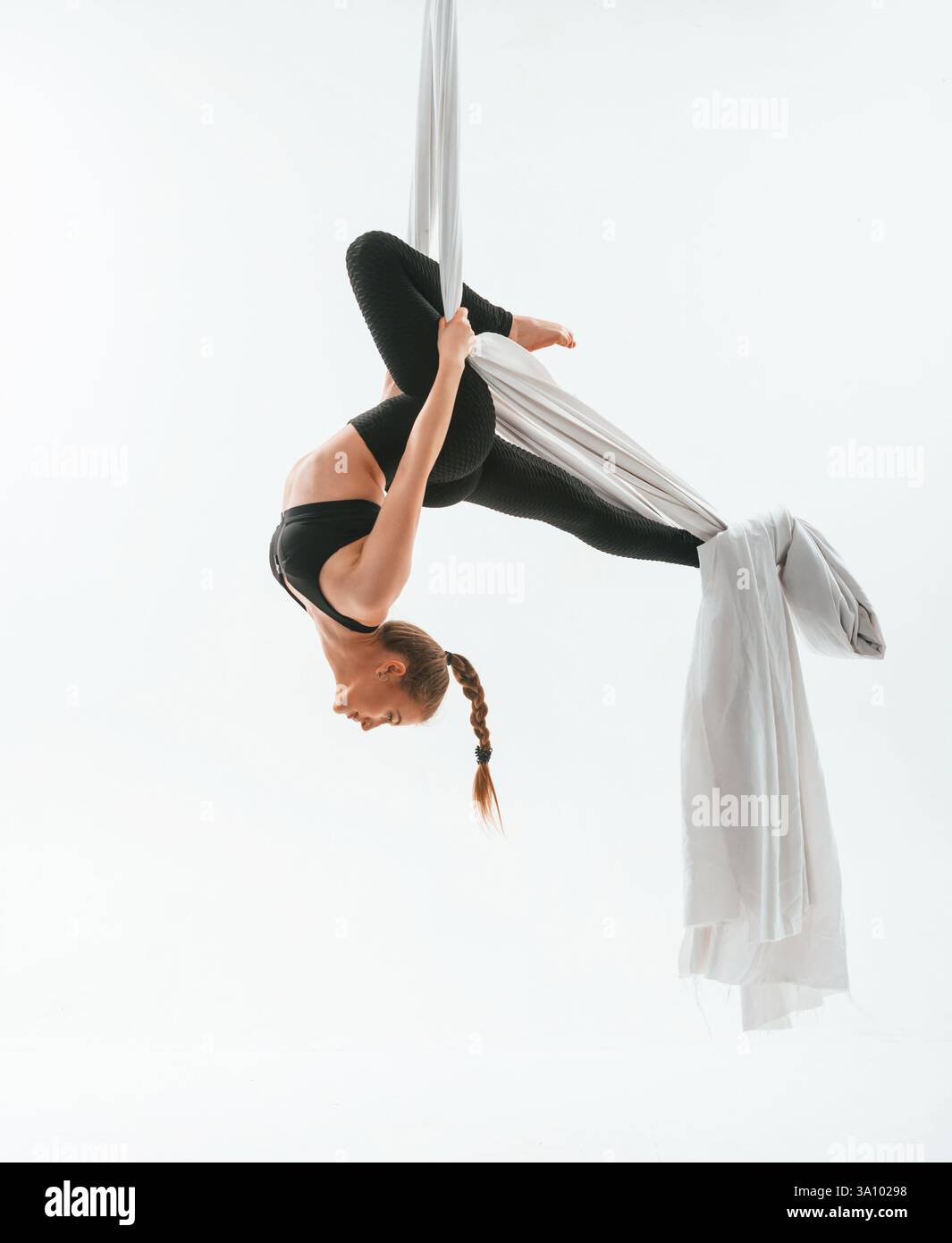 View from the side, hanging upside down. Young beautiful woman doing ...